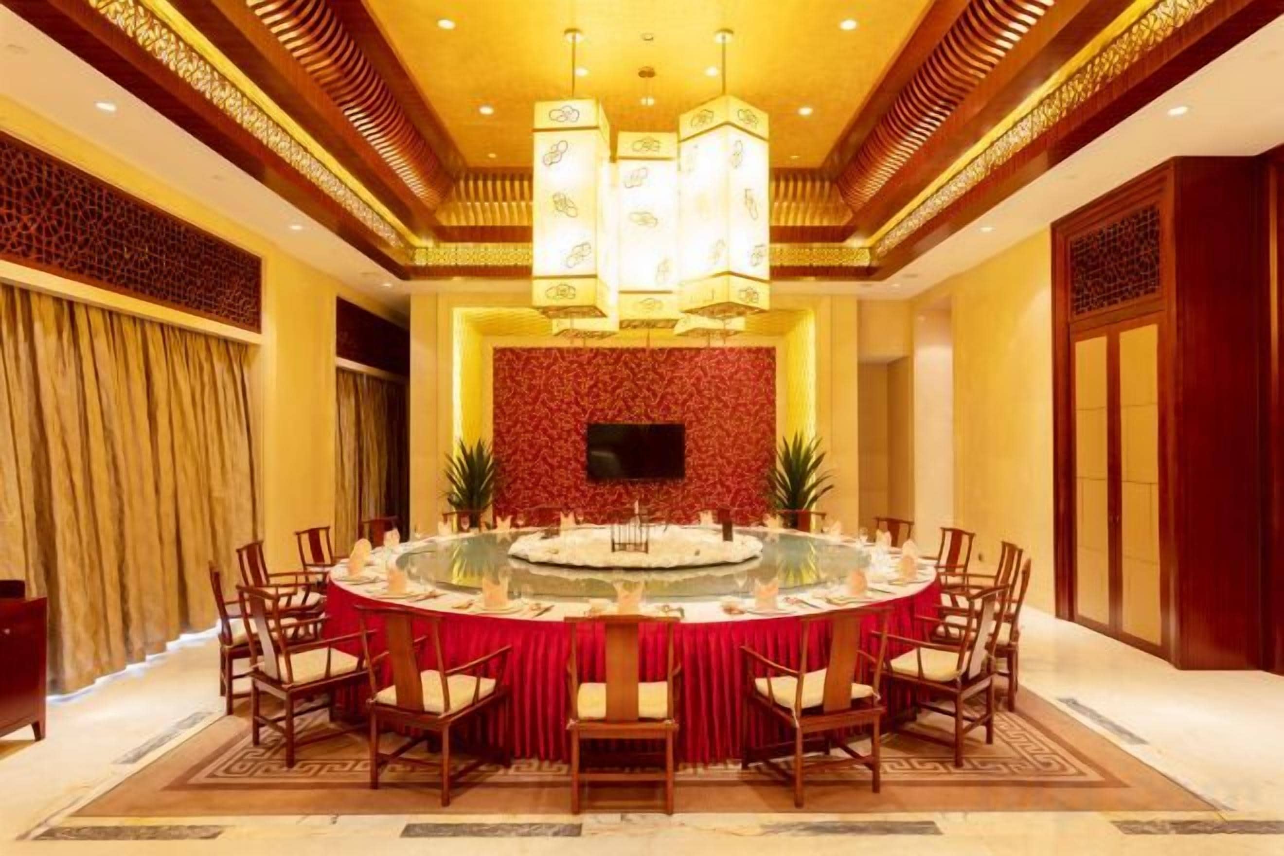 Uma mesa de jantar redonda com cadeiras, toalha de mesa vermelha e um candelabro.
