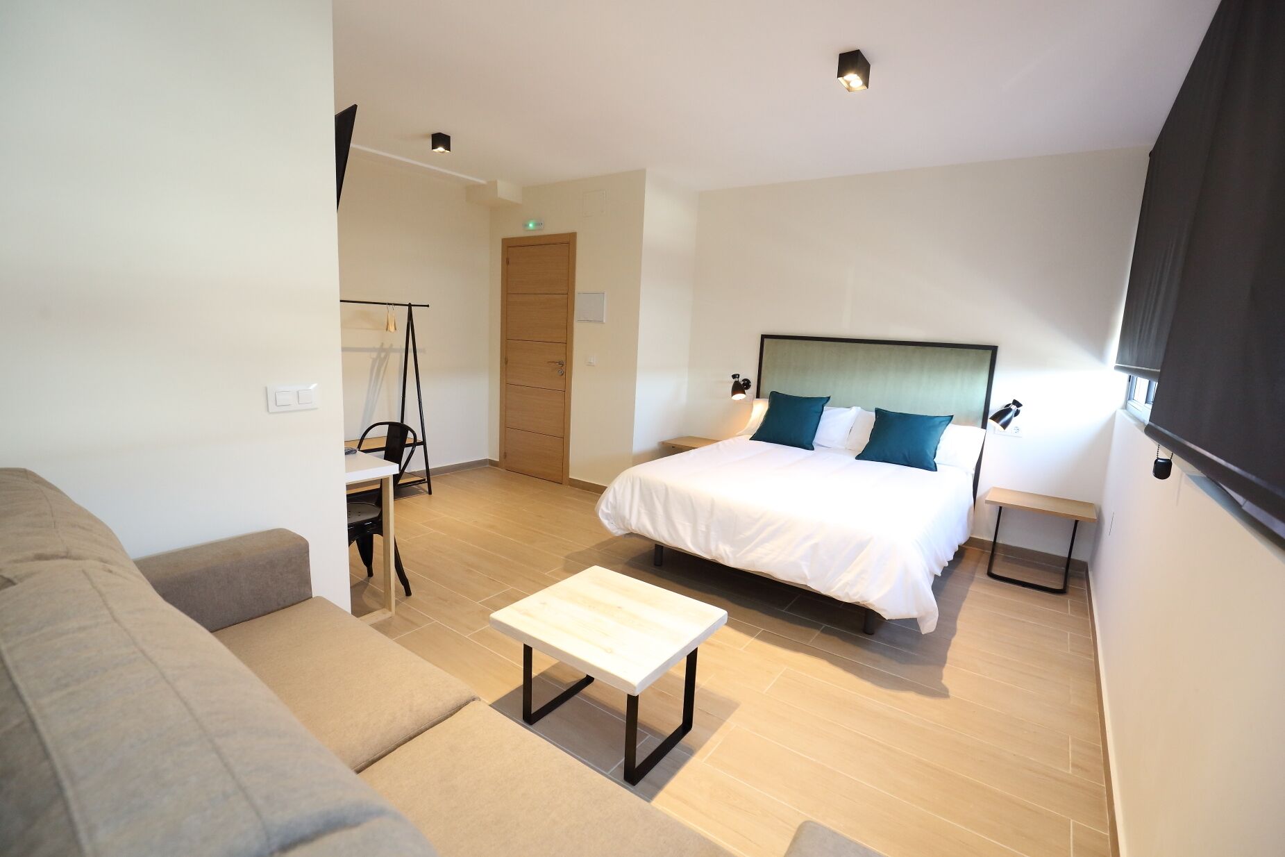 Quarto de hotel com uma cama, um sofá, uma mesinha e uma escrivaninha.