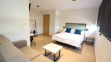 Quarto de hotel com uma cama, um sofá, uma mesinha e uma escrivaninha.