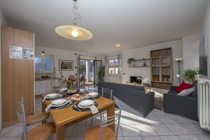 Uma sala de estar moderna com área de jantar, um sofá cinzento e um armário de madeira.