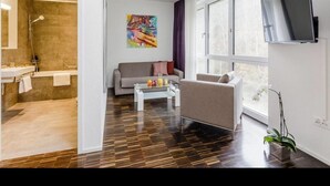 Uma sala de estar moderna com sofá, mesa de centro e televisão na parede.