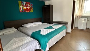 Quarto de hotel com duas camas, parede verde-água, um quadro, um guarda-roupa e uma janela com cortinas.