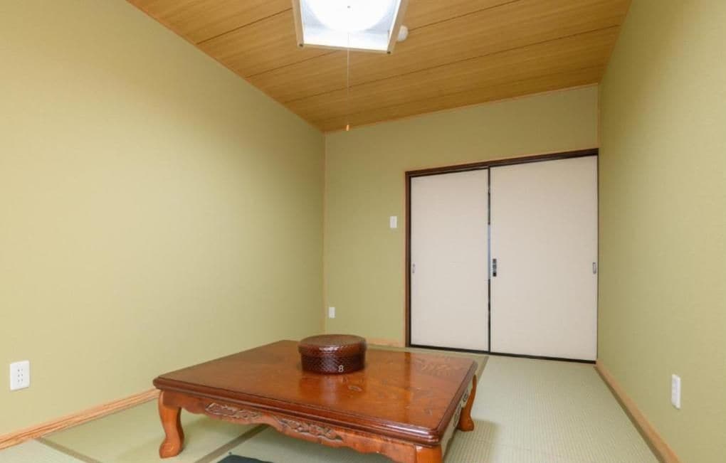 Um quarto japonês tradicional com tatames, uma mesa de madeira e portas deslizantes.