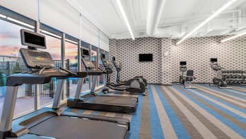 Academia com esteiras, elípticos e estações de musculação.