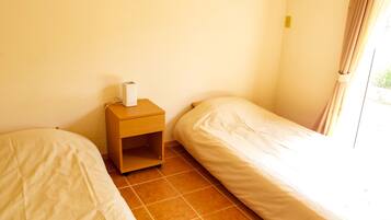 Acomodação compacta, com um quarto e duas camas individuais, mesa de cabeceira com abajur e janela com cortinas.
