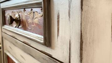 Um close-up de uma cômoda com um painel decorativo e uma gaveta com puxador de latão.
