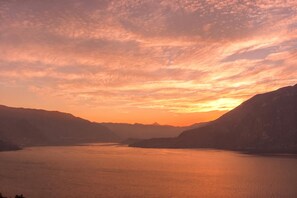 Vista panorâmica de um lago rodeado por montanhas ao pôr do sol.