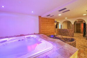 Uma área de spa com banheira de hidromassagem, piso de pedra e detalhes em madeira.