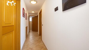 Um corredor com portas de madeira, piso de azulejos e uma placa na parede.