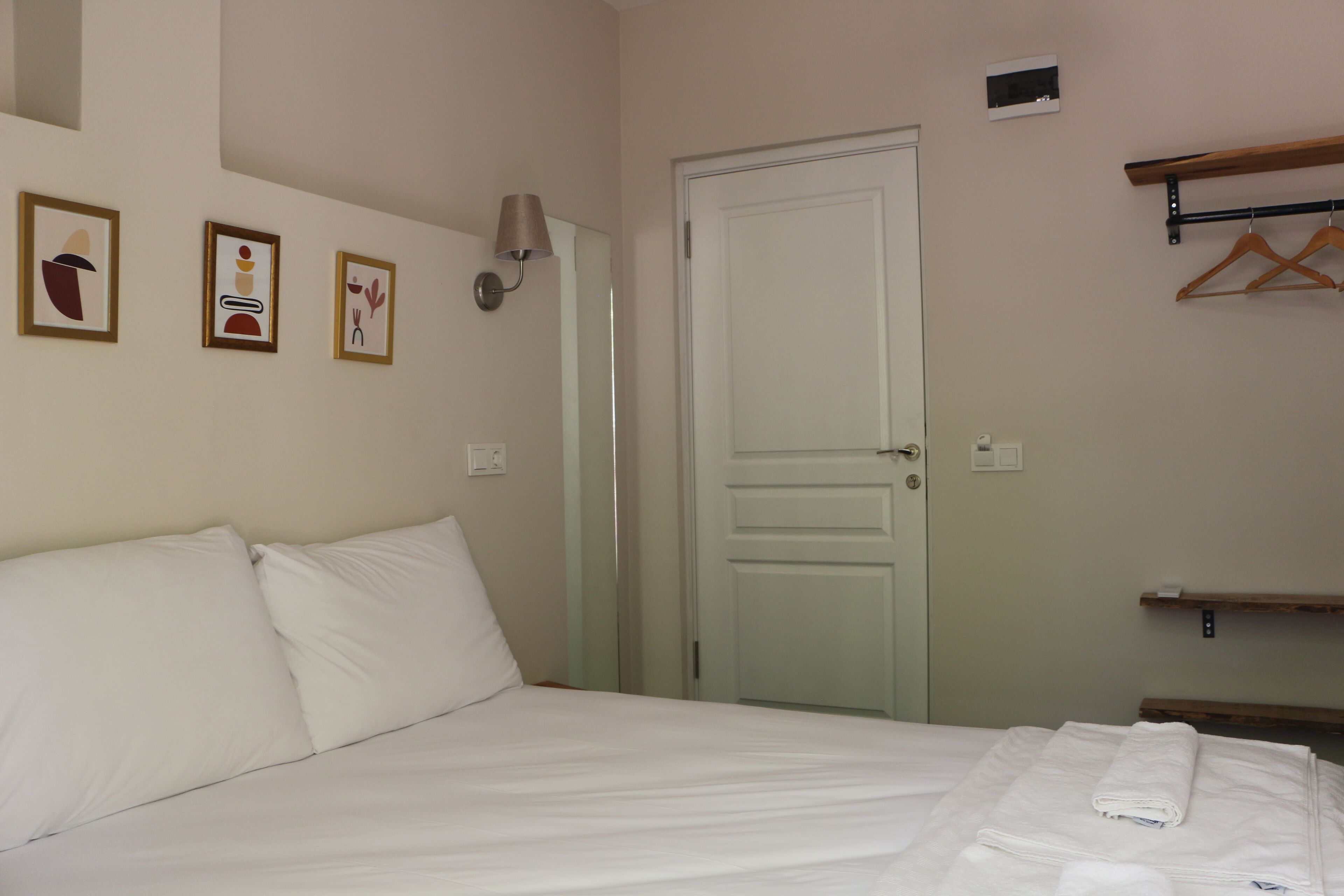 Quarto de hotel com uma cama, uma porta e um cabideiro.