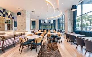 Restaurante moderno com paredes de mármore, grandes janelas e diversas opções de assentos, incluindo mesas e cabines.
