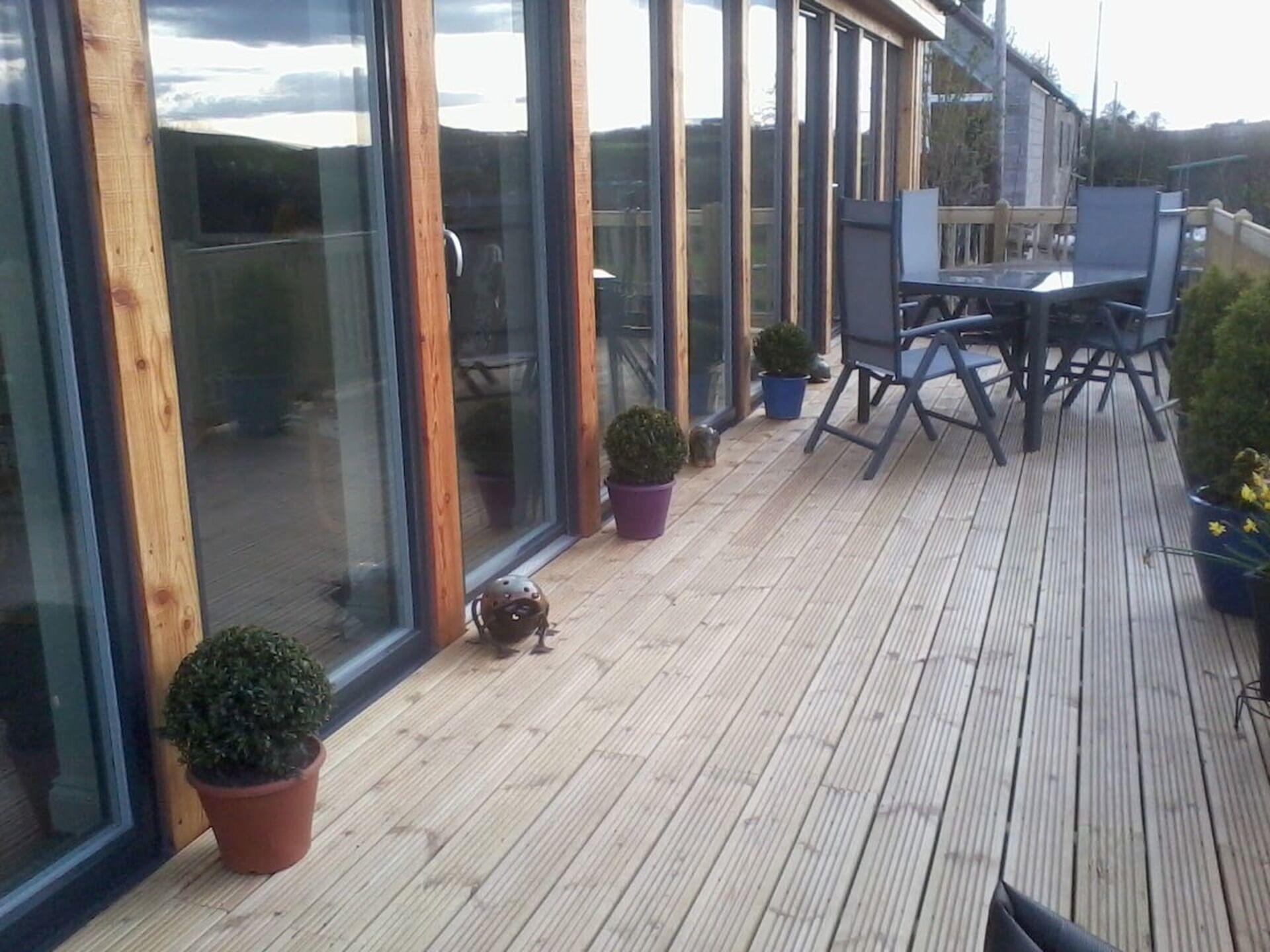 Um deck de madeira com portas de vidro e vasos de plantas.