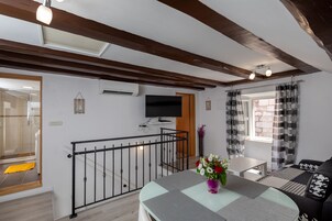 Uma sala de estar moderna com mesa de vidro, sofá estampado em preto e branco e teto de madeira.