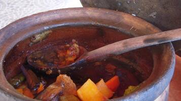 Um pote de barro rústico cheio de ensopado, com pedaços de carne e legumes.