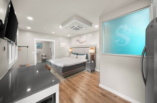 Quarto de hotel moderno com cama, mesa de cabeceira e uma janela grande.