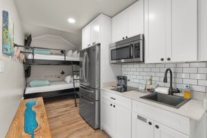 Quarto de hotel compacto com cozinha compacta, beliche e pequena área de refeições.
