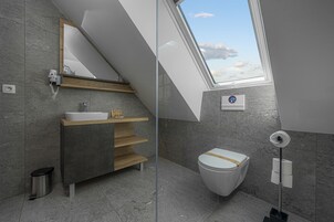 Uma casa de banho moderna com um claraboia, um lavatório de madeira, sanita e um cestinho de lixo.
