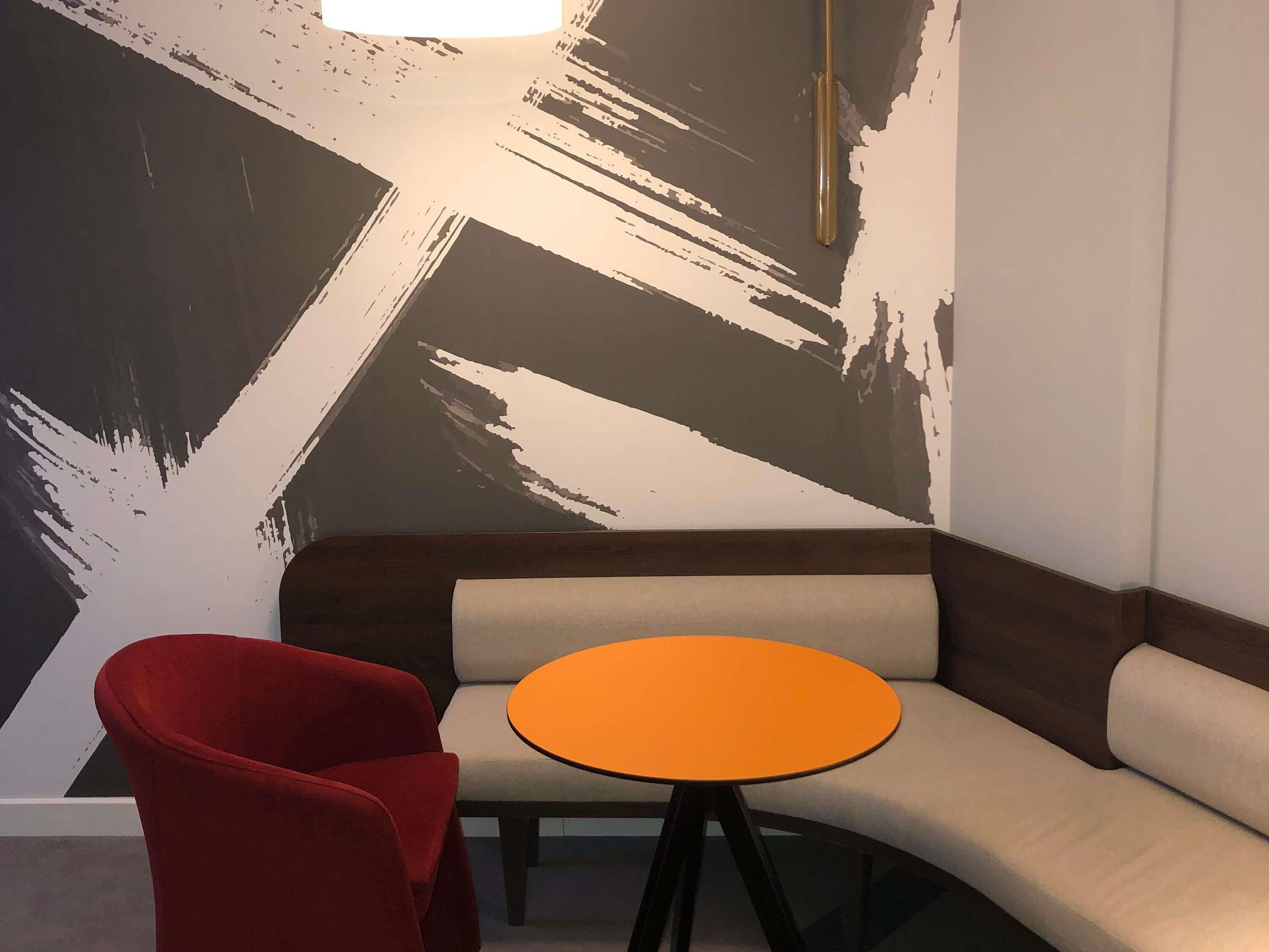 Quarto moderno com sofá e uma pequena mesa laranja.