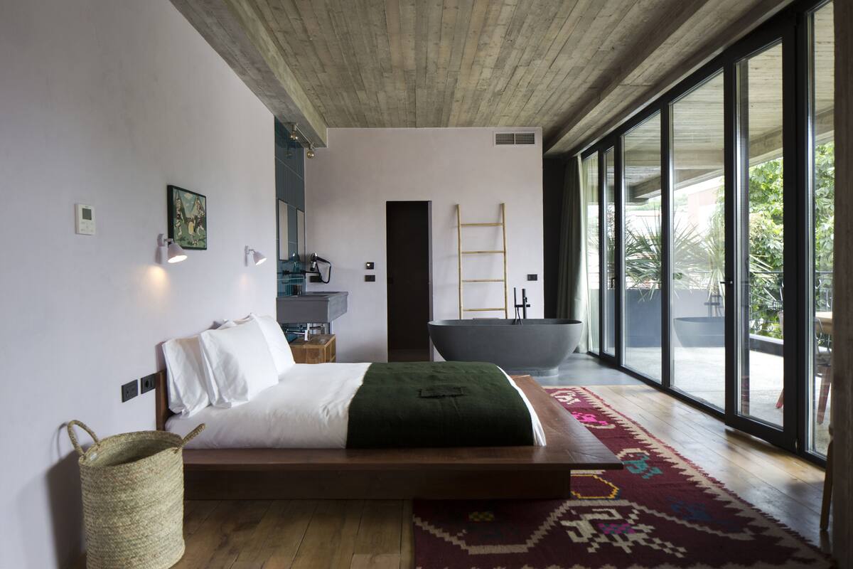 Quarto moderno com uma cama grande, uma banheira e vista para o exterior.