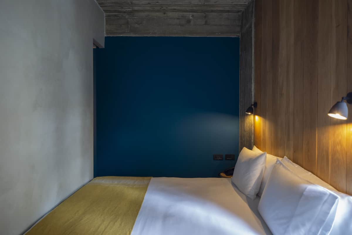 Um quarto pequeno com uma cama, parede de madeira e parede azul.