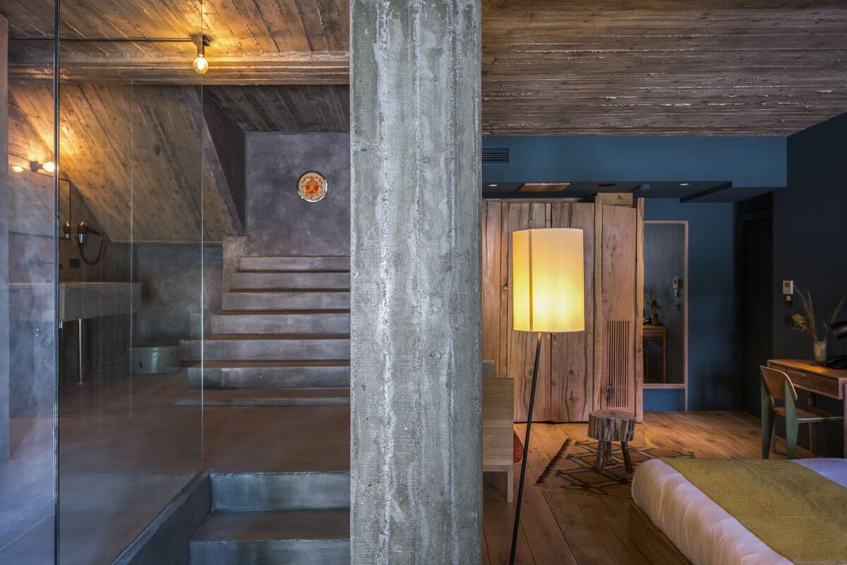 Um interior moderno com uma escada, uma luminária grande e uma cama.