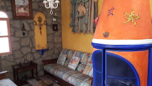 Uma sala de estar aconchegante com parede de pedra, mesa de madeira, sofá azul e lareira colorida.