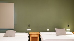 Quarto com duas camas, mesas de cabeceira de madeira e paredes verdes.