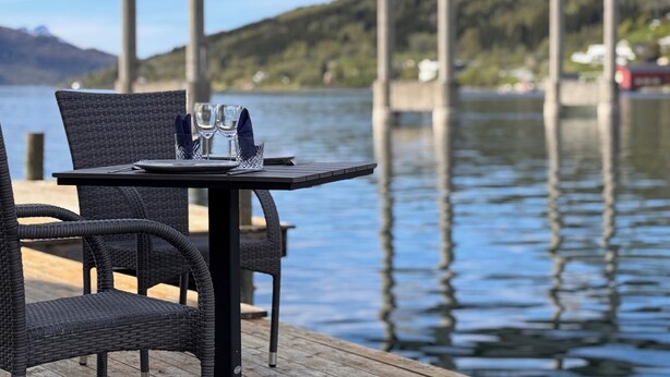 Uma mesa de jantar com cadeiras e vista para um lago.