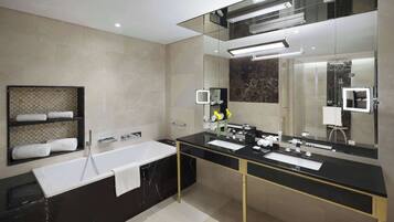 Uma casa de banho moderna com um lavatório preto e dourado, um espelho grande e uma banheira separada.