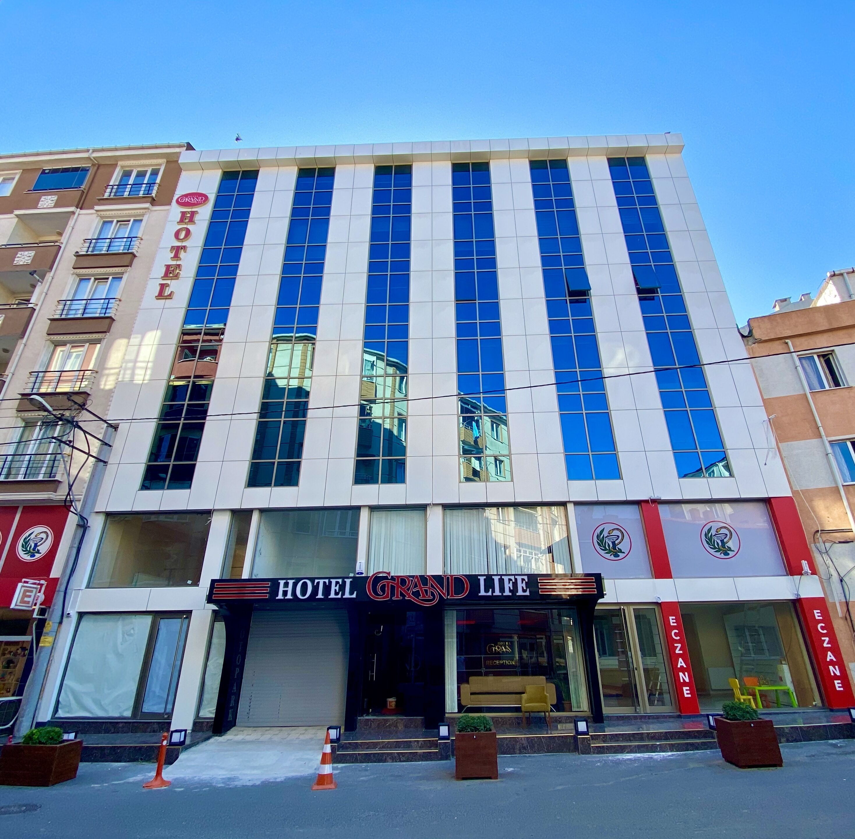 Um edifício de hotel moderno com um letreiro chamativo 'HOTEL GRAND LIFE' na entrada.