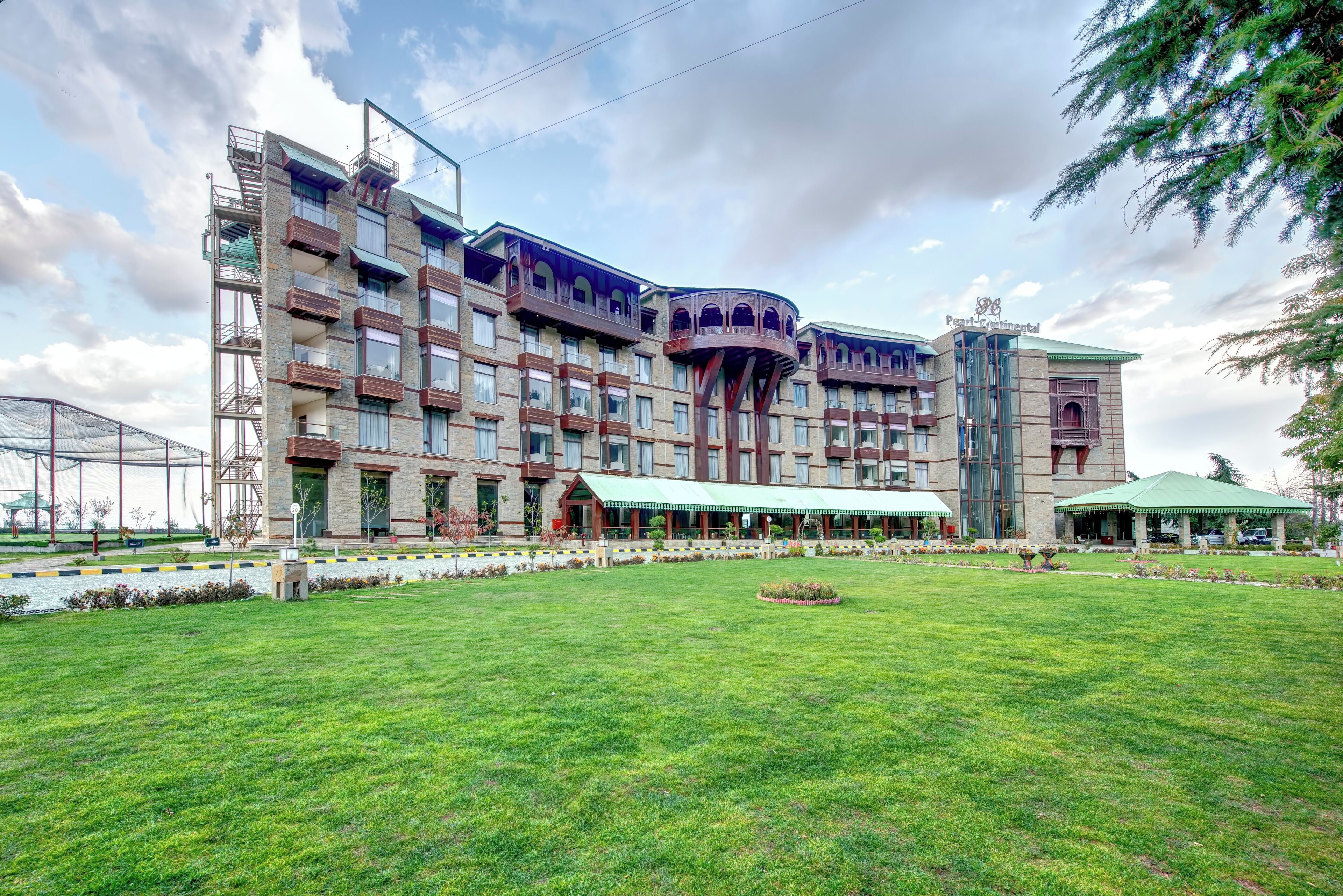 Um hotel com vários andares, um pátio central, varandas e uma área de estar coberta ao ar livre.