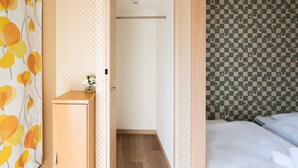 Quarto com cama, guarda-roupa de madeira e banheiro com porta-toalhas.