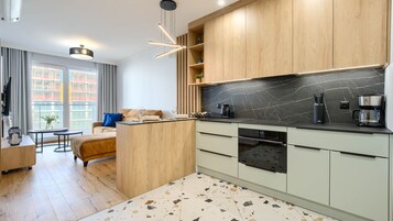 Uma cozinha moderna com armários de madeira, painel de fundo de mármore preto e uma cafeteira.