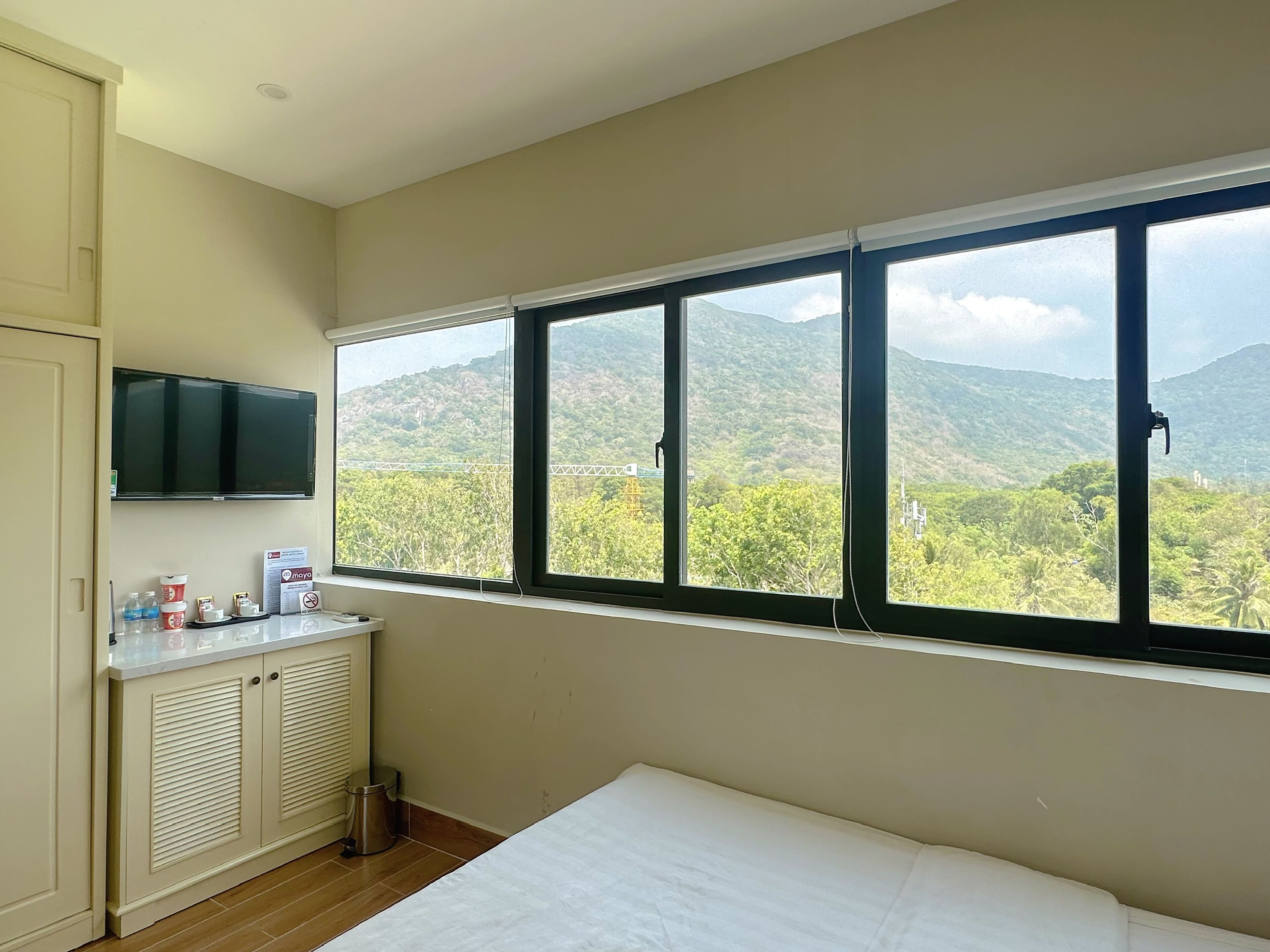 Quarto com uma grande janela com vista para uma paisagem montanhosa.