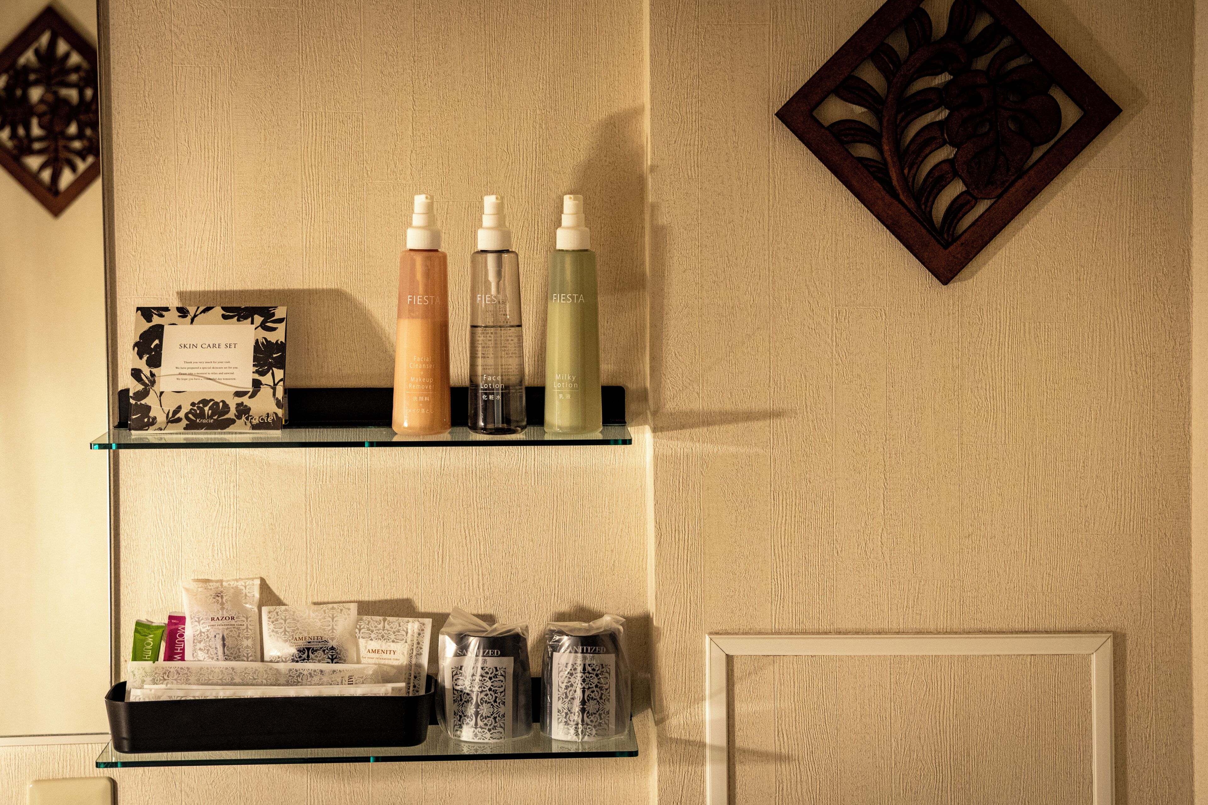 Um banheiro com uma prateleira de vidro exibindo produtos de higiene pessoal, um cartão emoldurado e um objeto decorativo na parede.