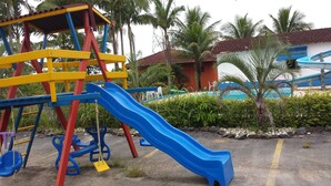 Um parquinho com um escorrega azul, balanços e uma estrutura de escalada.
