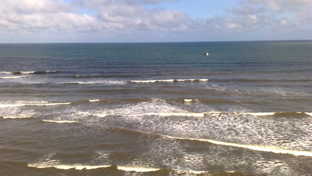 Vista do oceano com ondas e um boia distante.