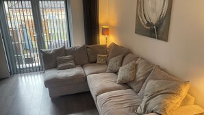 Uma sala de estar com um sofá seccional bege, um abajur e um quadro na parede.
