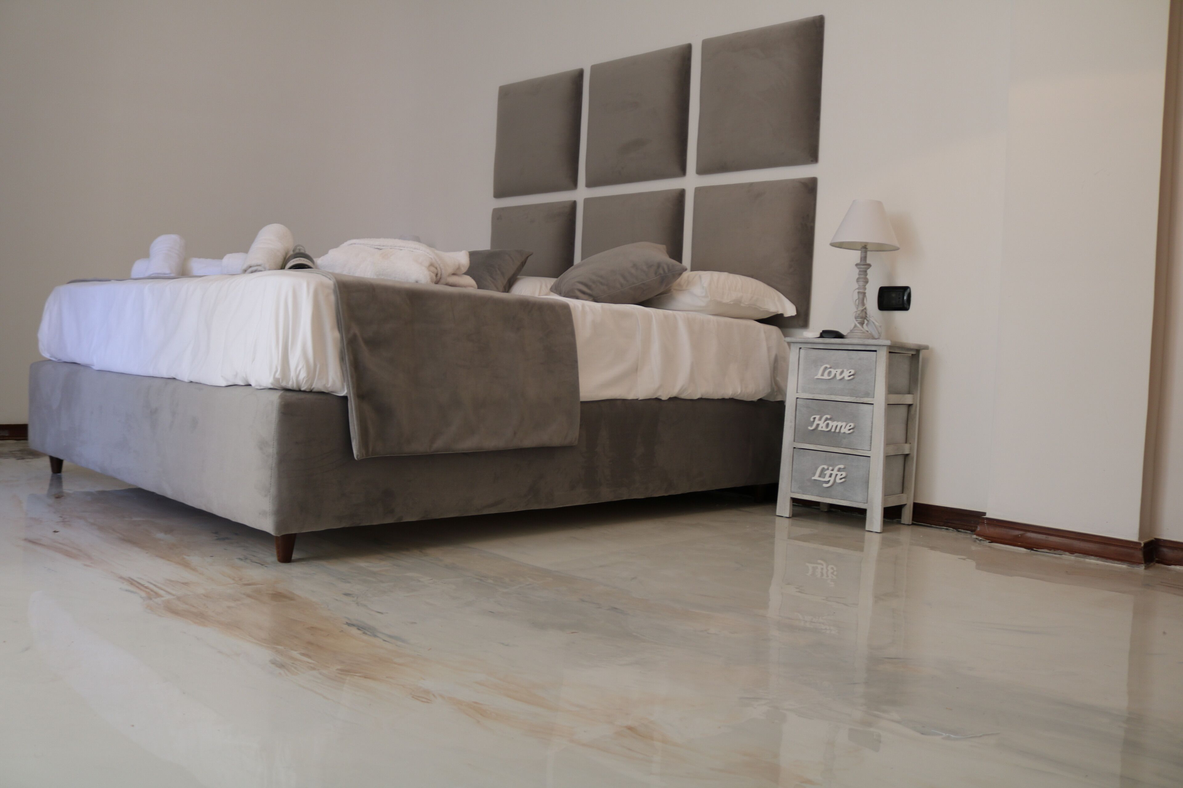 Um quarto moderno com uma cama grande, uma mesinha de cabeceira e uma luminária fixada na parede.