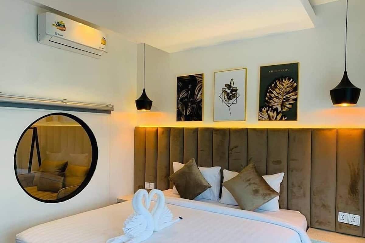 Quarto de hotel com uma cama grande, um espelho redondo e obras de arte penduradas na parede.