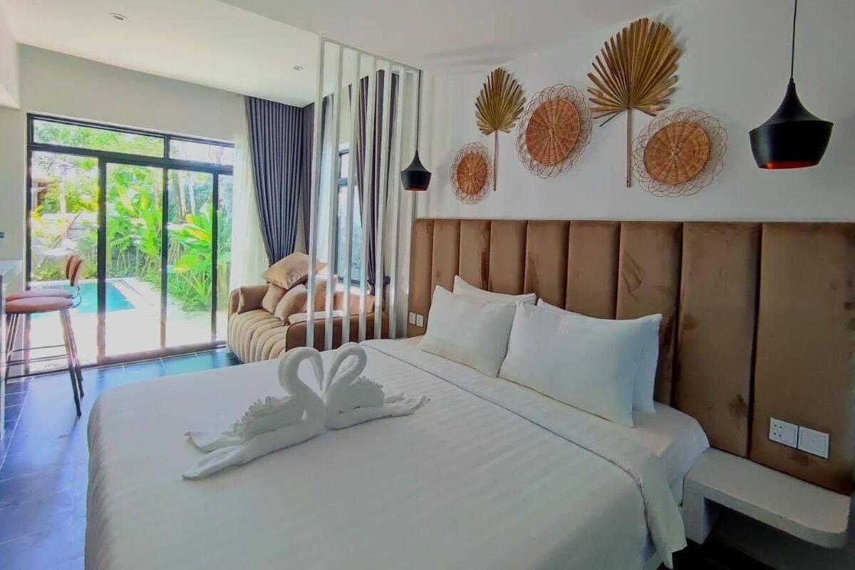 Quarto de hotel com uma cama grande, vista para o exterior e uma varanda com uma cadeira.