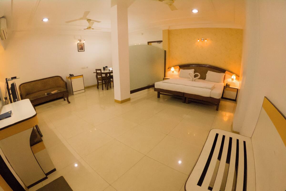 Quarto de hotel com cama, sofá, mesa de jantar e uma cadeira.