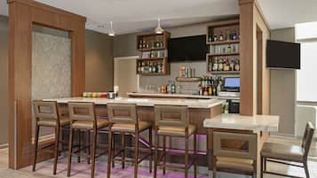 Uma cozinha moderna com área de bar, armários de madeira e uma TV de tela plana.