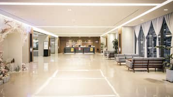 Um hall amplo com balcão de recepção, área de estar e um pinheiro de Natal.