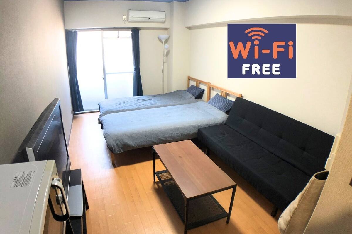 Quarto com cama, sofá, pequena mesa e sinalização indicando acesso à internet.