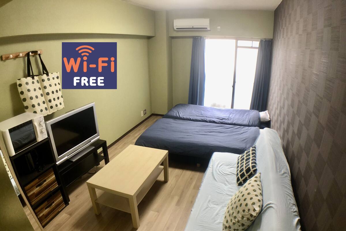 Um quarto com cama, sofá, televisão e sinal de Wi-Fi.