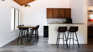 Uma cozinha moderna com armários de madeira, uma ilha central com banquetas e uma área de jantar com mesa e cadeiras.