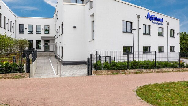 Um edifício branco moderno com uma placa que diz 'Aparthotel Am Pfaffenstein'.