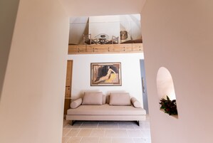 Uma sala de estar moderna com um sofá bege, uma pintura na parede e estrutura de teto em madeira.