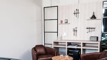 Um interior moderno com um carro, poltronas de couro, uma parede com painel perfurado e uma mesa de madeira.